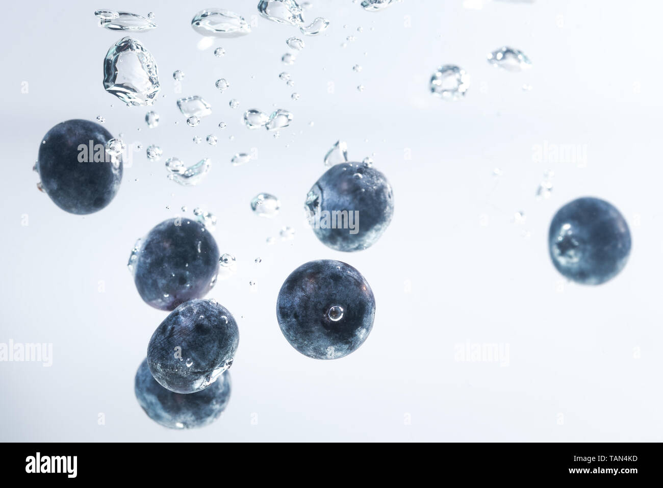 Organic blueberries sinking into water with air bubbles on white ...