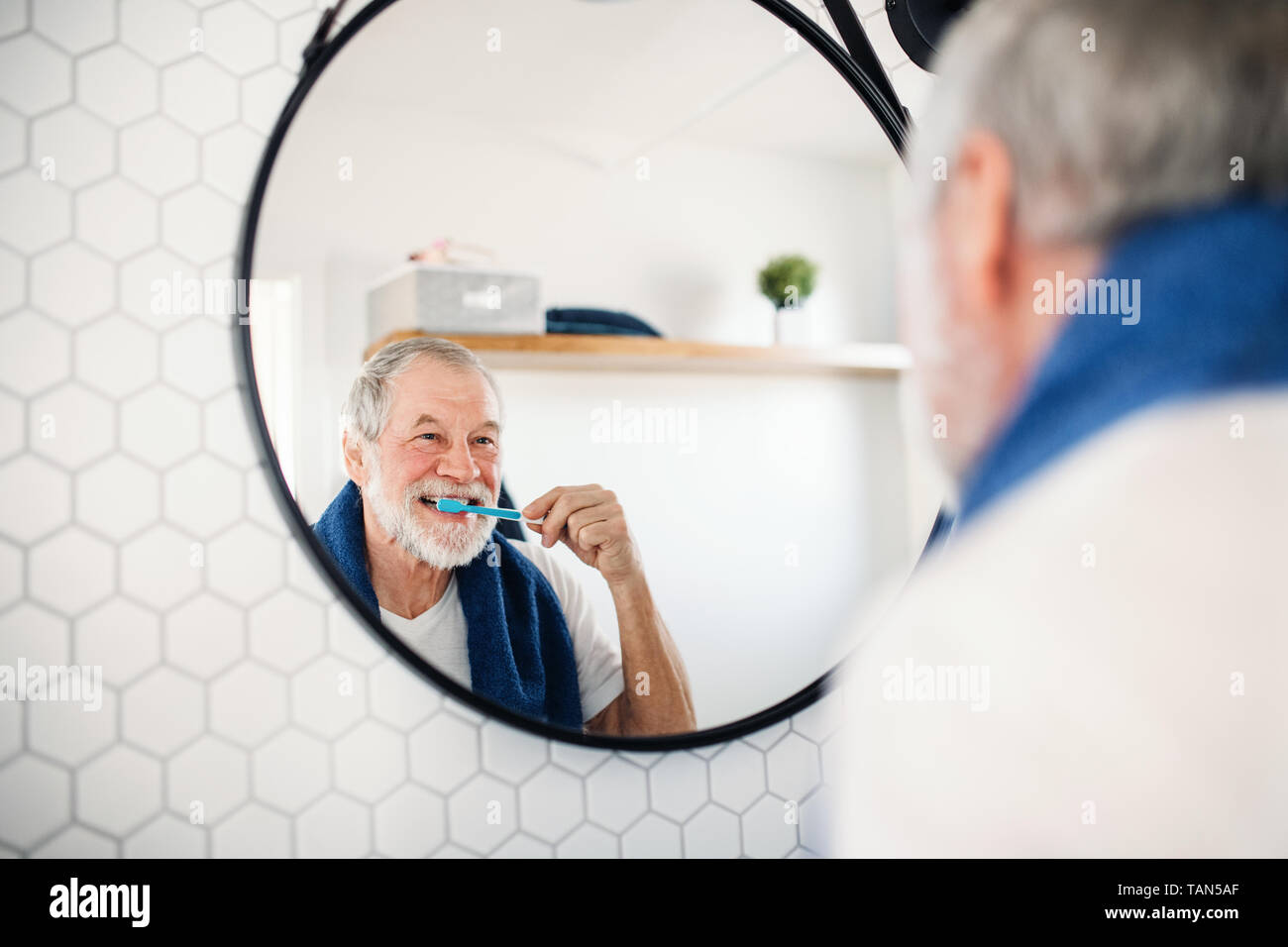 A senior man brushing teeth in bathroom indoors at home. Copy space ...