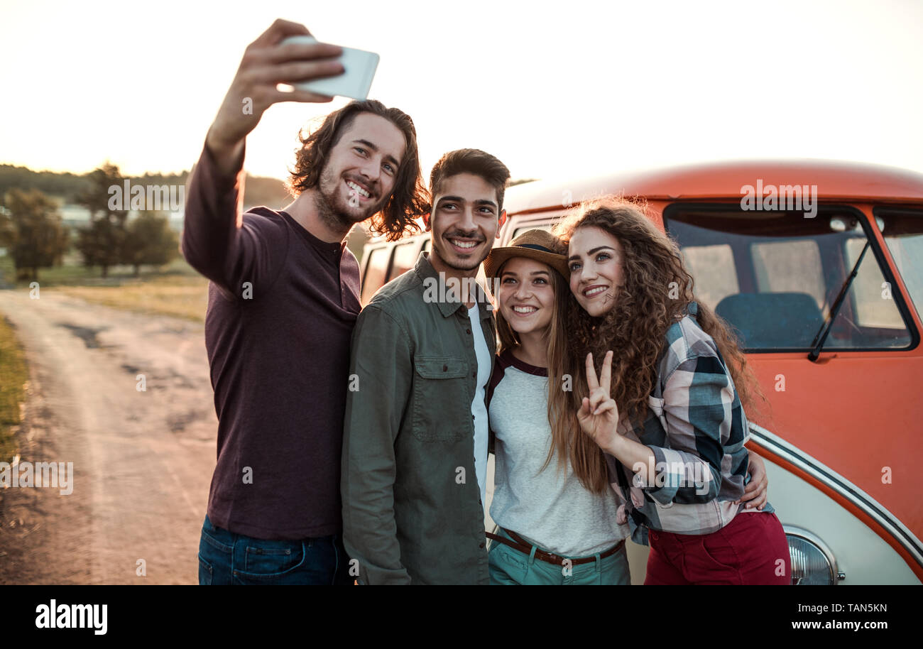 A group of young friends on a roadtrip through countryside, taking ...