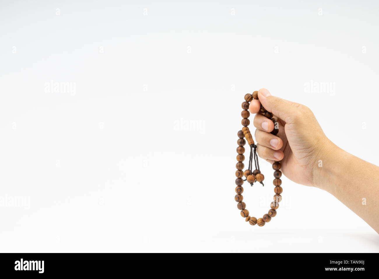 Hand holding a muslim rosary beads or Tasbih on white background. Copy ...