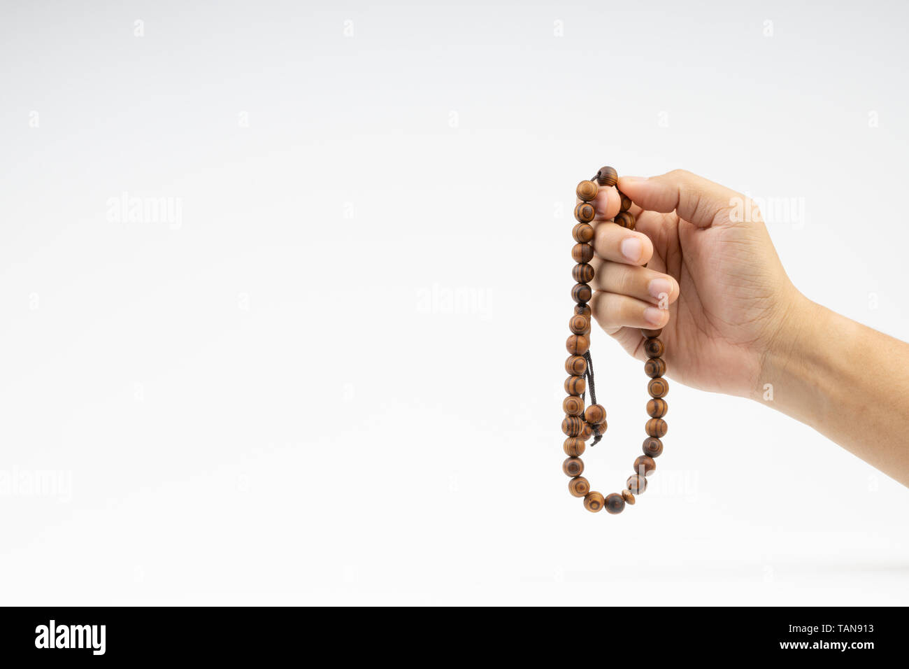 Hand holding a muslim rosary beads or Tasbih on white background. Copy ...