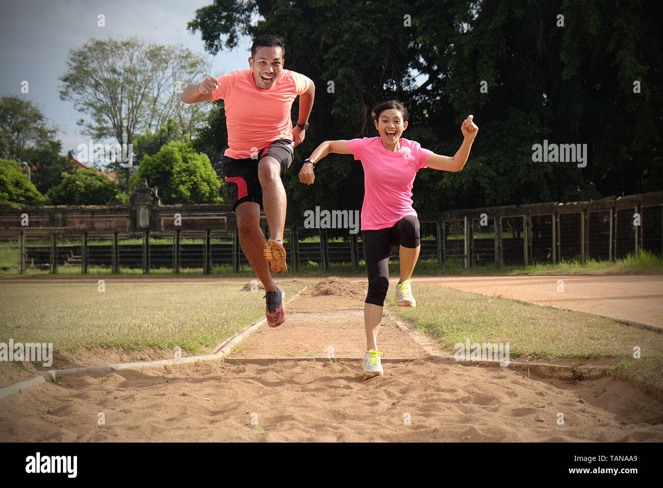 Two sports partners are jogging together on a sunny day wearing orange ...