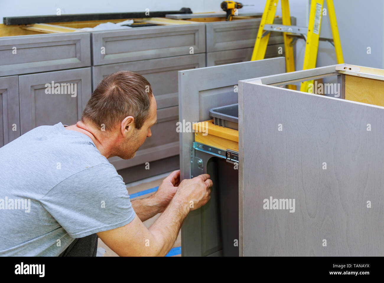 A carpenter is building a drawers garbage bin in the kitchen using a ...