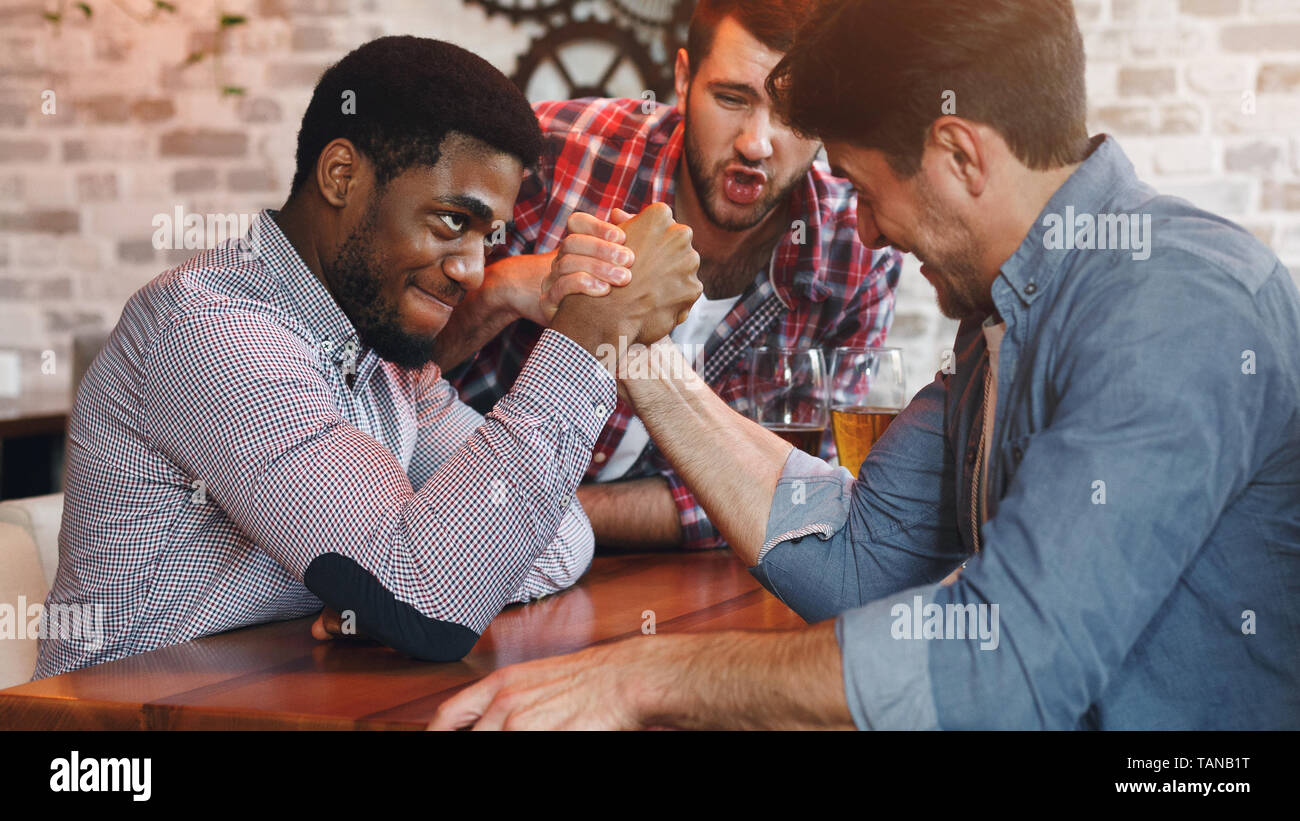 Diverse Friends Arm Wrestling And Drinking Beer At Bar Stock Photo - Alamy