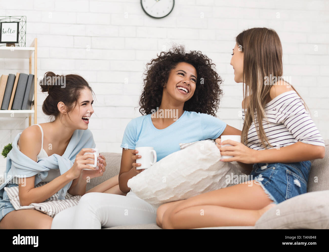Female roommates gossiping and laughing, drinking coffee Stock Photo ...