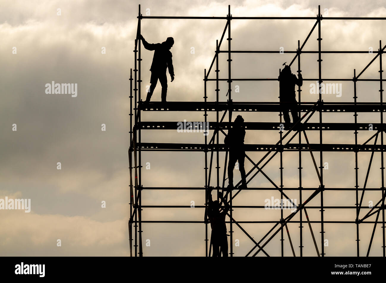 Construction workers silhouette working on iron platform sky background ...