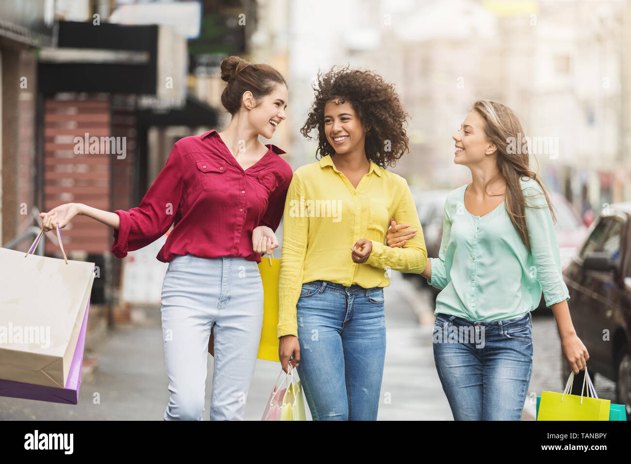 Girls walking along city street after shopping Stock Photo - Alamy