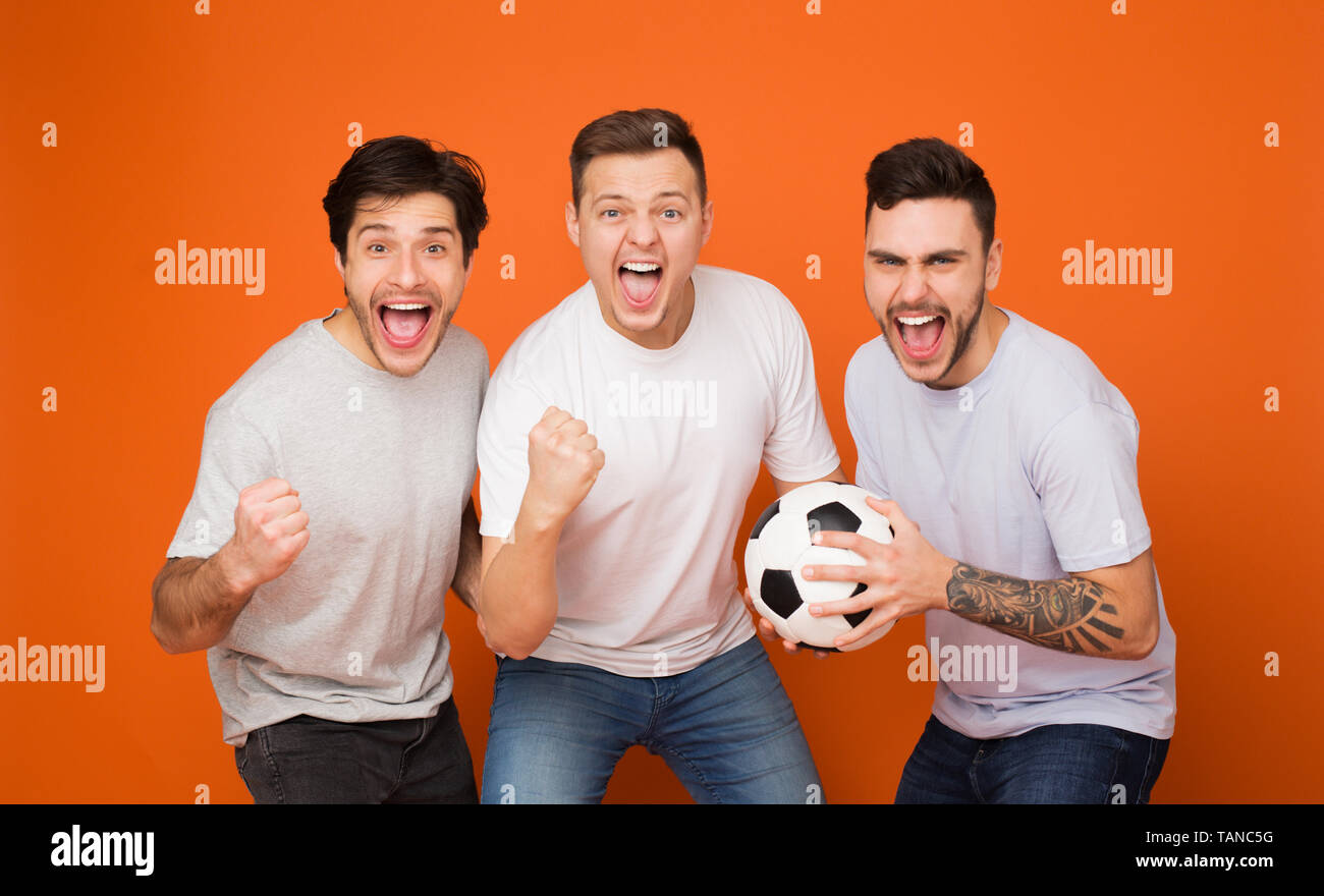 Football Fans. Men Holding Soccer Ball, Orange Background Stock Photo ...