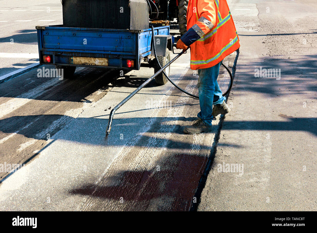 The road maintenance worker sprays the bitumen mixture onto the cleaned ...
