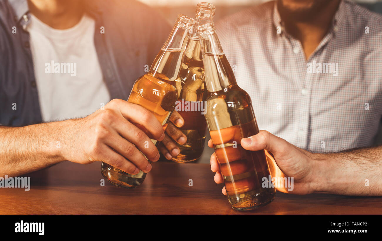 Mates Clinking Bottles Of Beer In Pub Stock Photo - Alamy