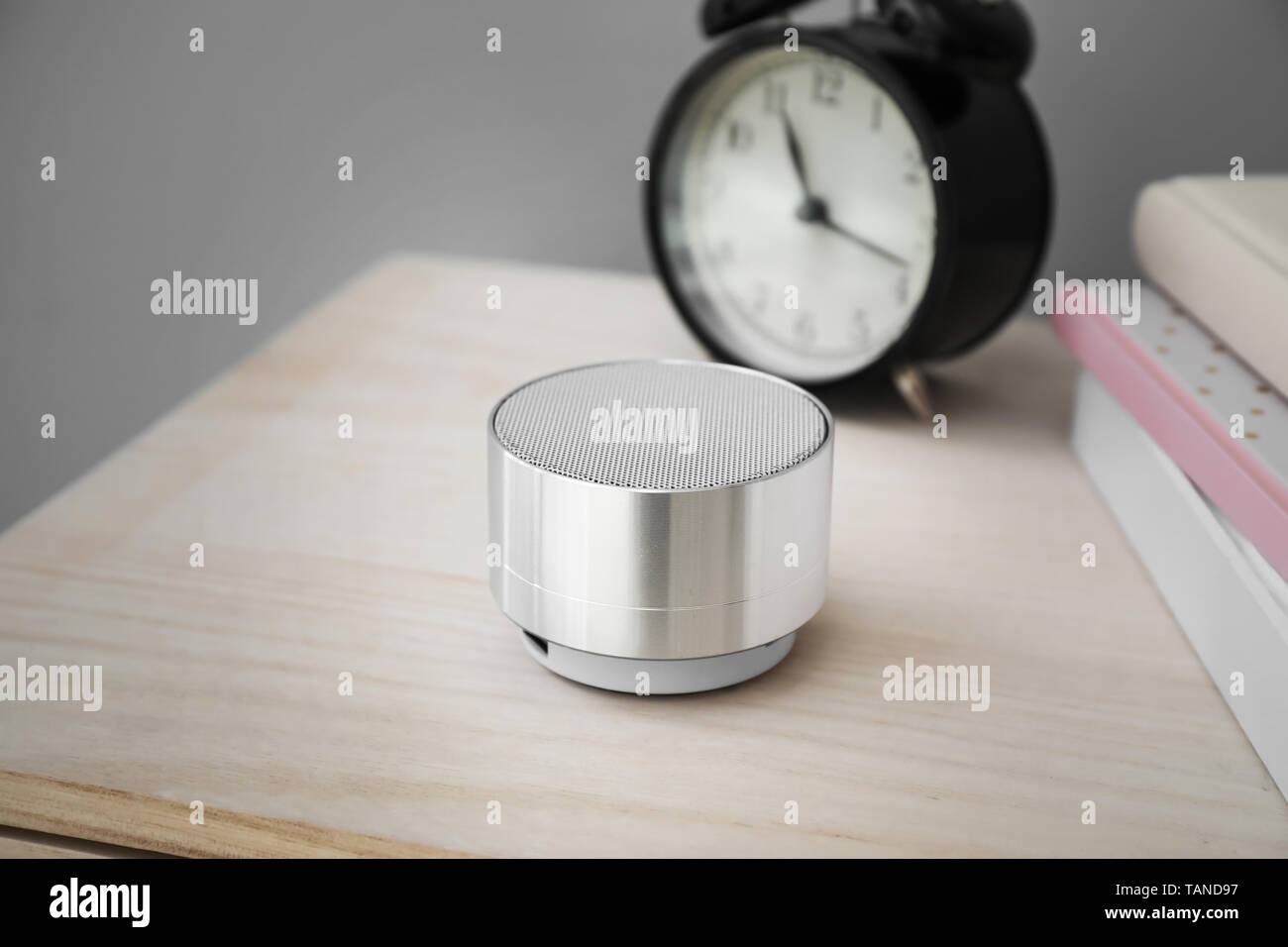 Smart home assistant device and clock on table against grey background ...