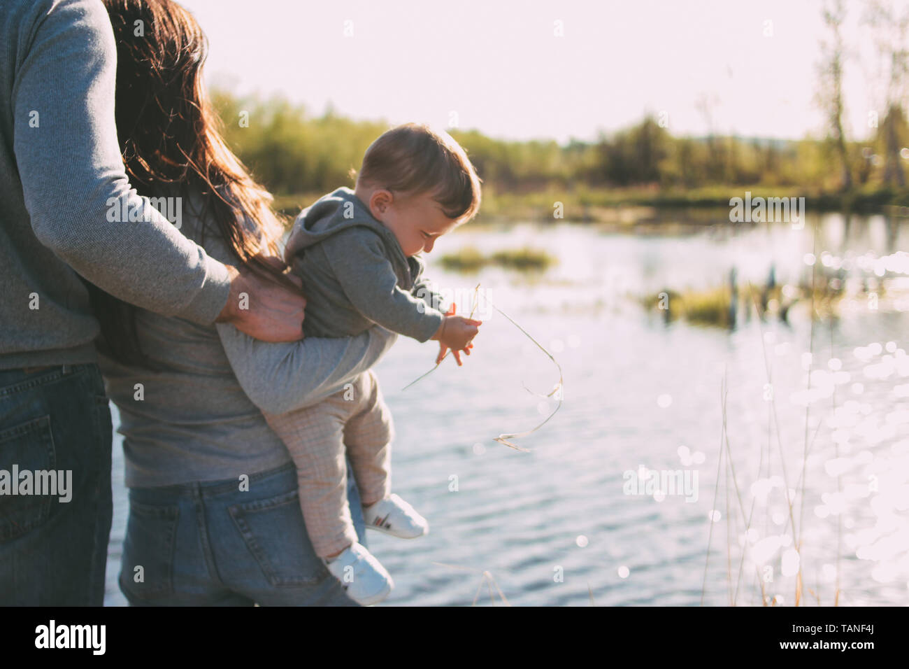 Happy family with Cute baby boy on the lake water background outdoors ...