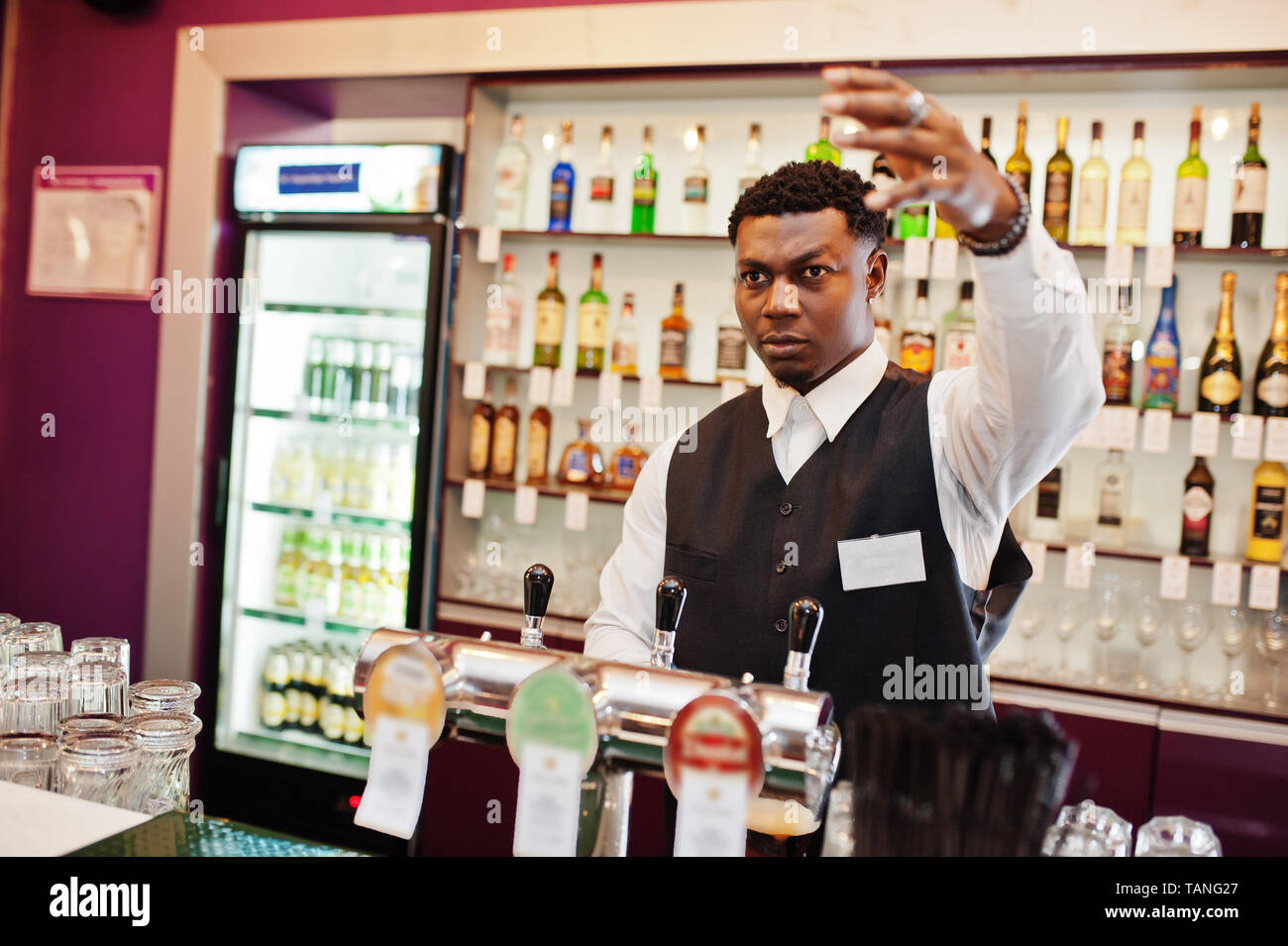 African american bartender at bar pouring from tap fresh beer into the ...