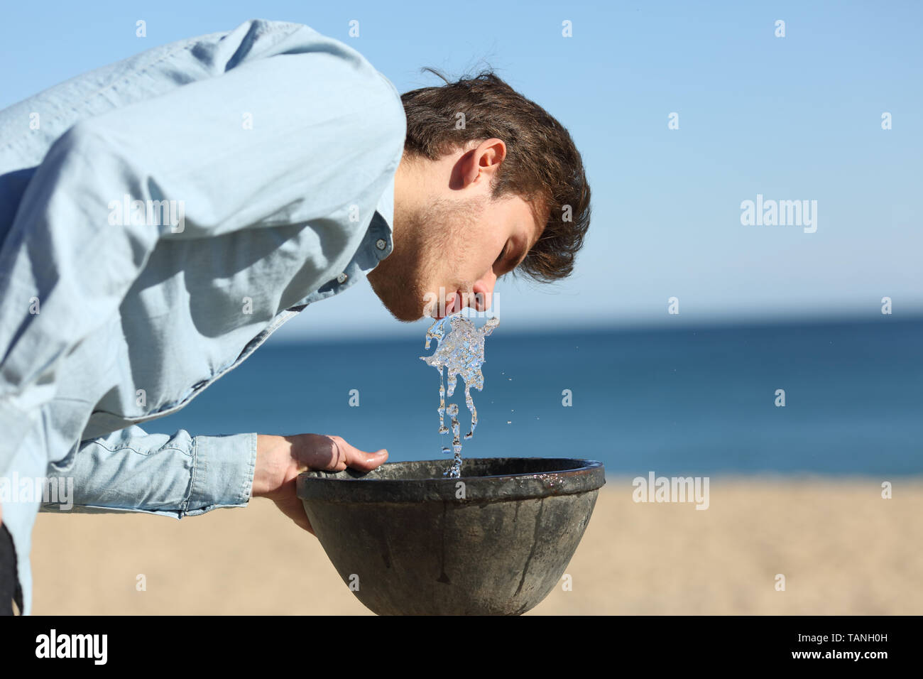 Casual man drinking water from a fountain on the beach Stock Photo - Alamy