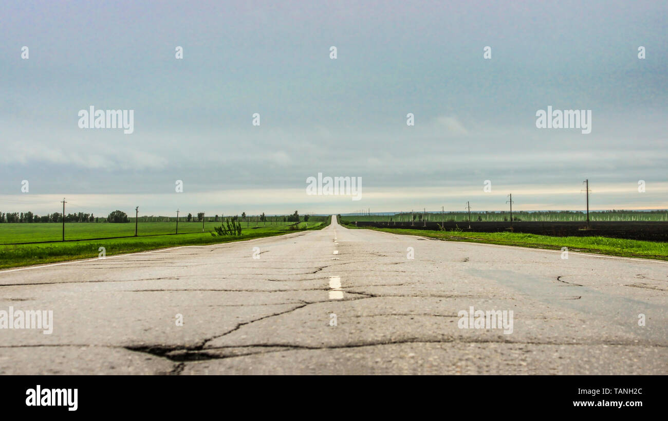 Landscape with a view of the old empty asphalt road through the fields ...