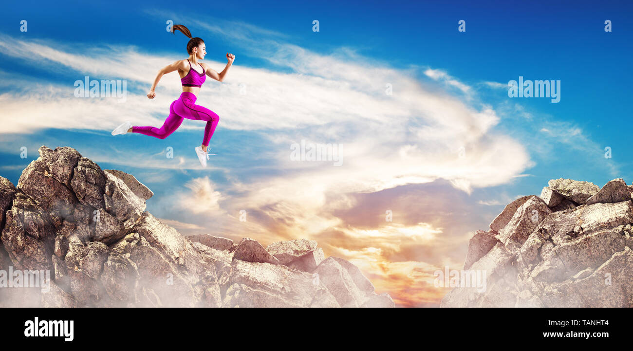Sporty woman jump through the gap between hills over sky background ...