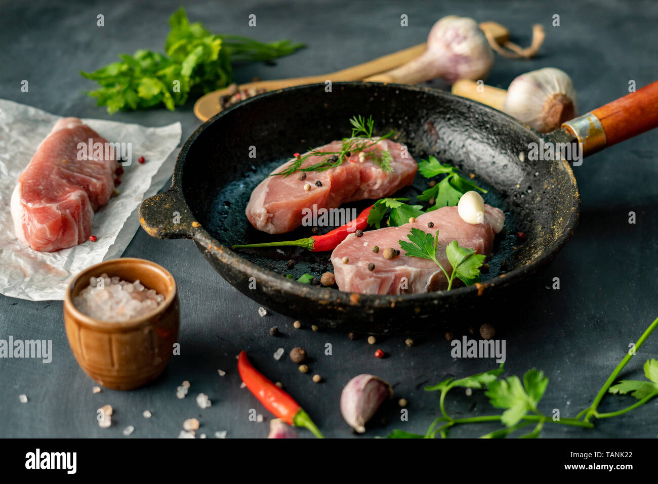 raw pork slices or steaks in a hot frying pan at the kitchen , rustic ...