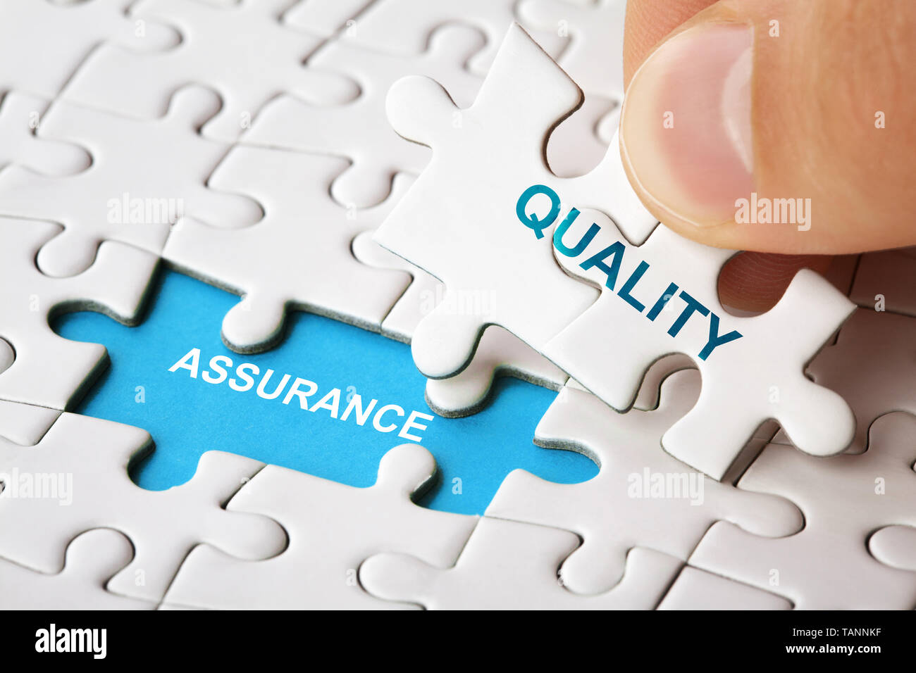Hand holding piece of puzzle with word QUALITY ASSURANCE Stock Photo ...