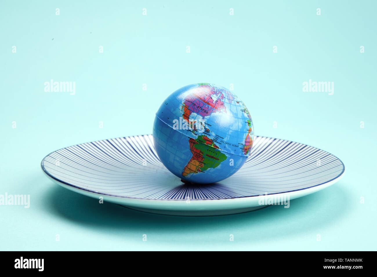 an earth planet ball placed on a target plate on a turquoise background ...