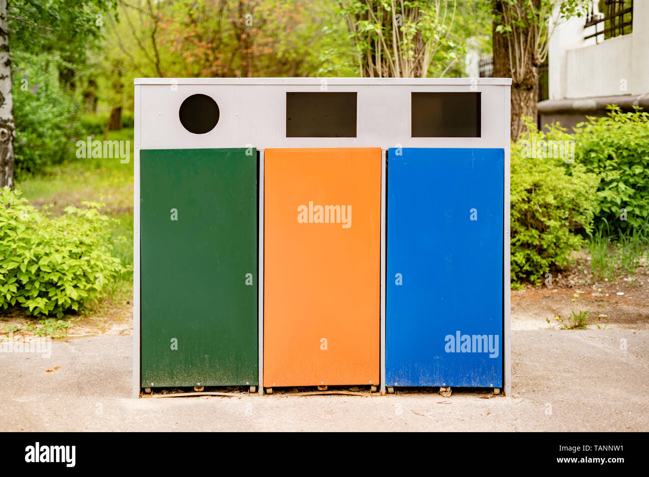 three different colorful metal trash bins or containers, garbage ...