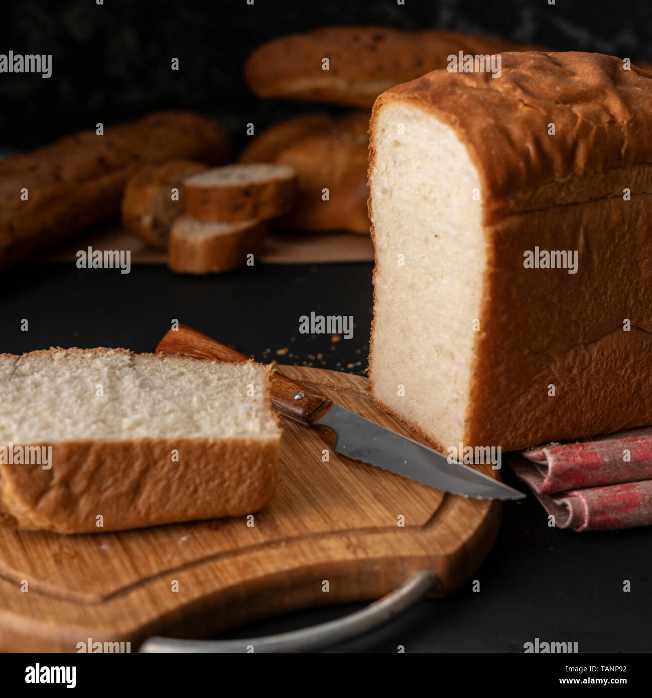 freshly baked sliced white bread with metal knife, toasts for cooking ...