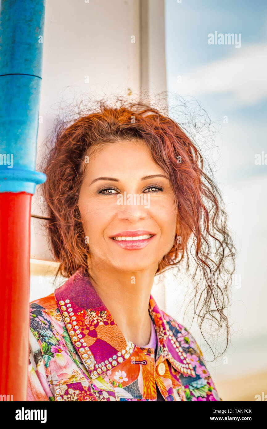 closeup of mature Mediterranean woman with gypsy red hair and tanned ...