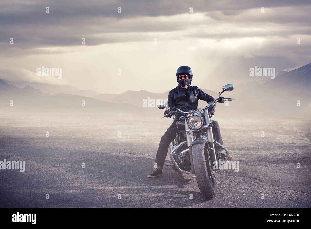 Side view of a young male biker sitting on the side of the road against ...