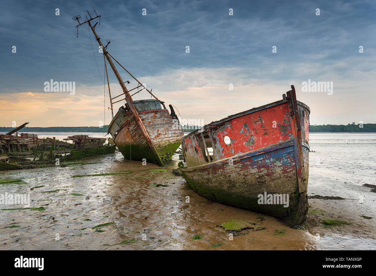 Old boat wrecks under a stormy sky on the River Orwell at Pin Mill on ...
