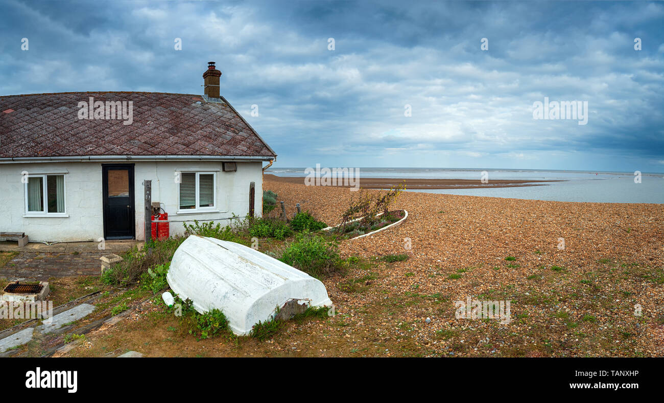 A cottage on the beach under a moody sky at Shingle Street on the ...