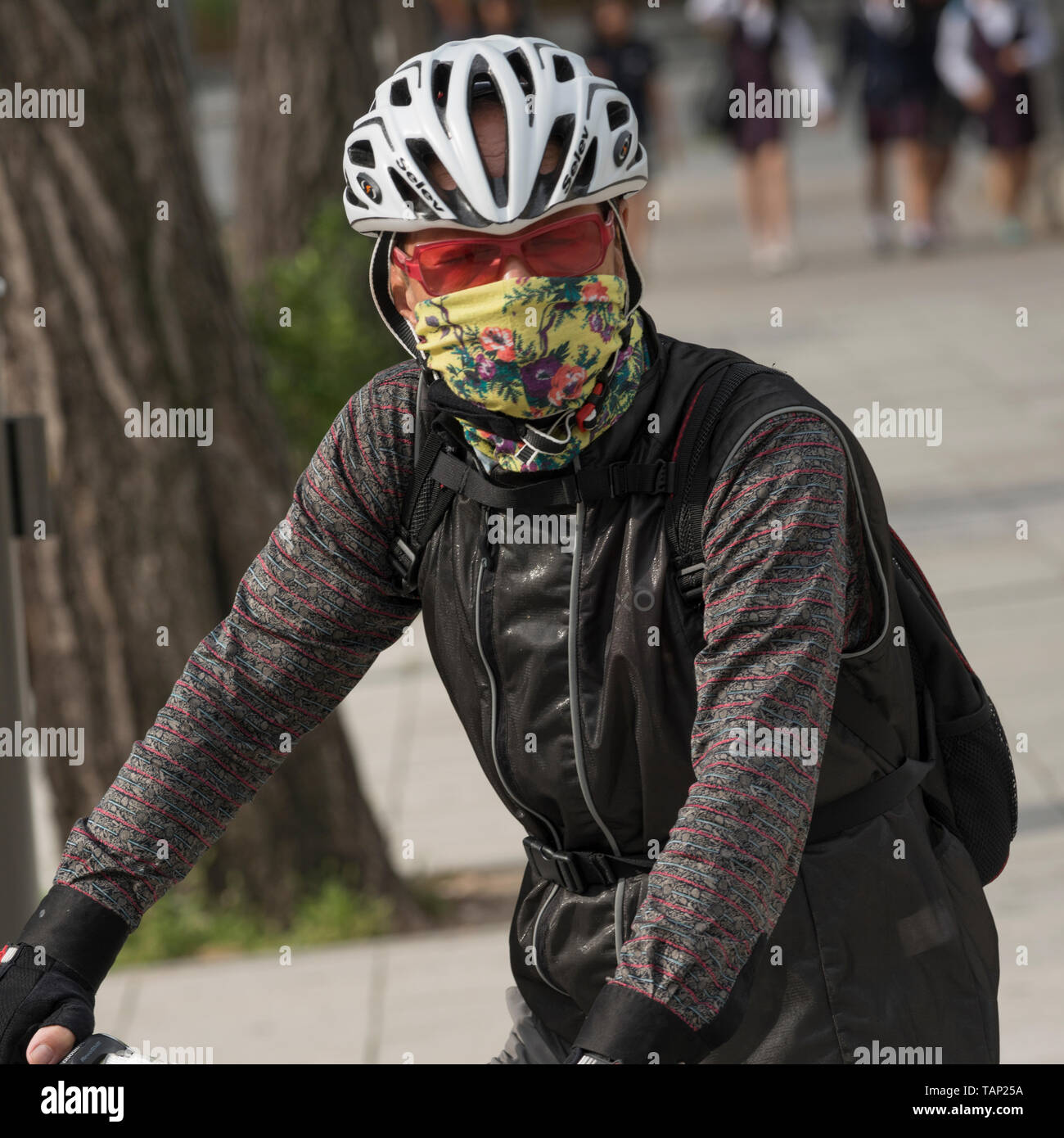 Person wearing a mask and helmet riding bicycle, Seoul, South Korea ...