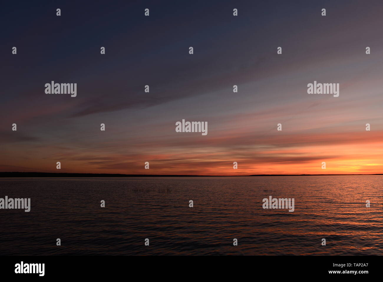 Cloudy sky in the twilight glow of the sun on the horizon above the ...