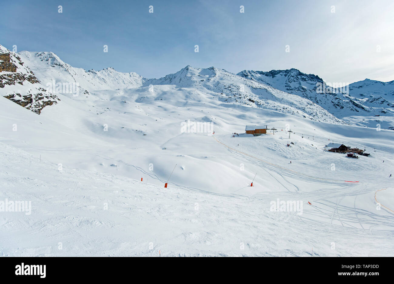 Panoramic view down snow covered valley across ski piste in alpine ...