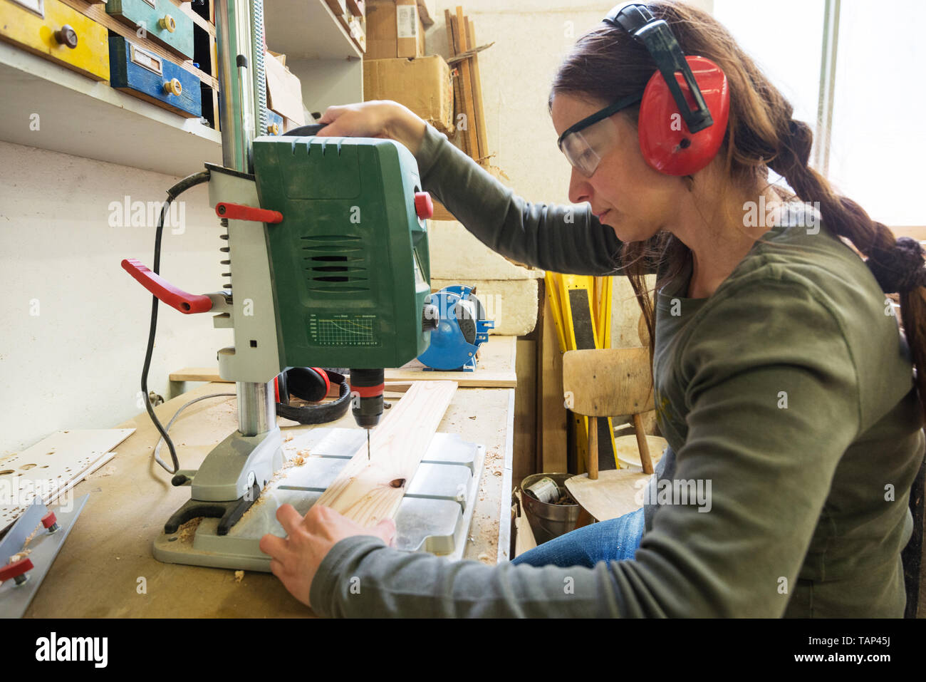 Young woman with drill perforating wood plank at workshop Stock Photo ...