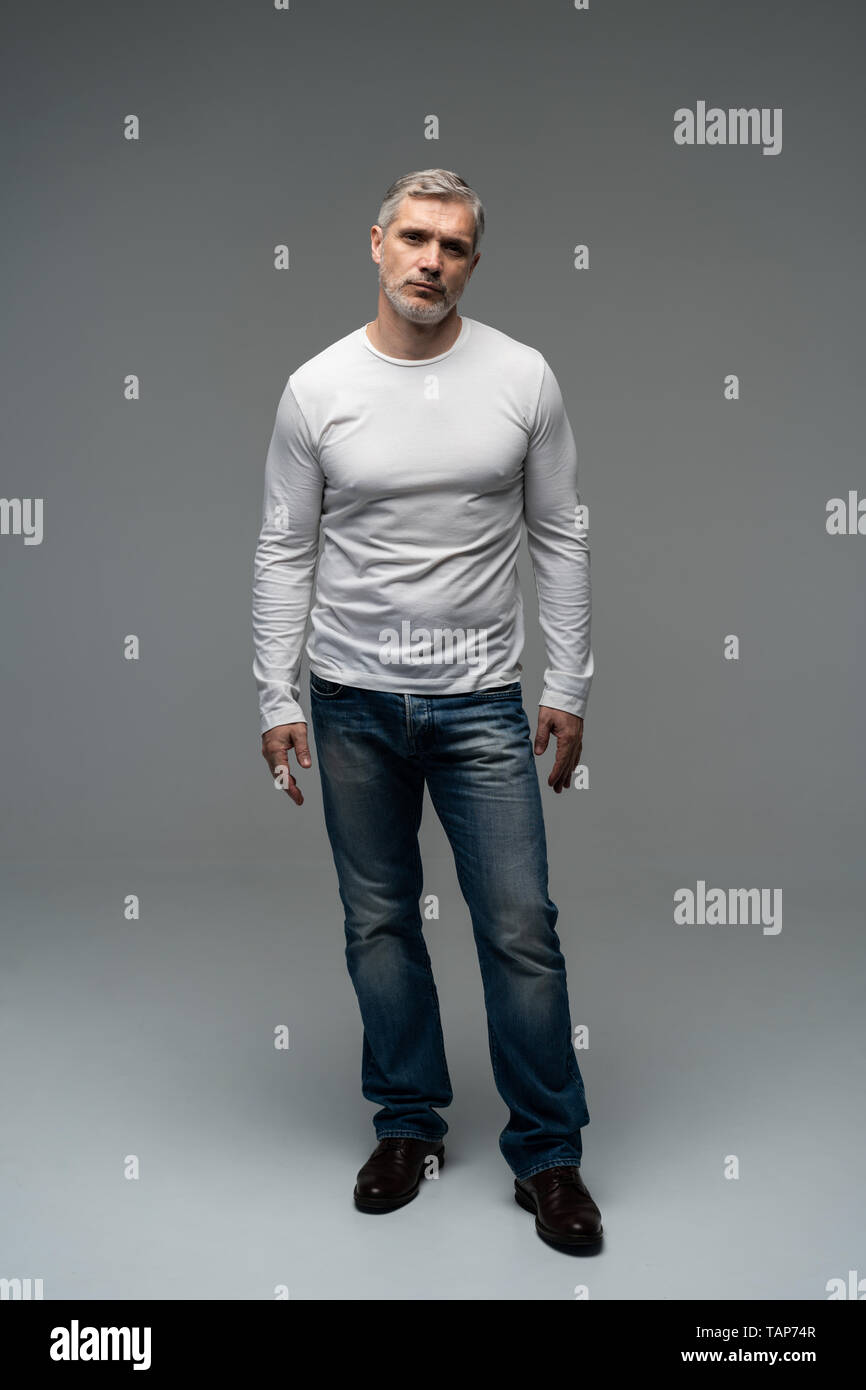 Full body portrait of relaxed mature man standing over gray background ...