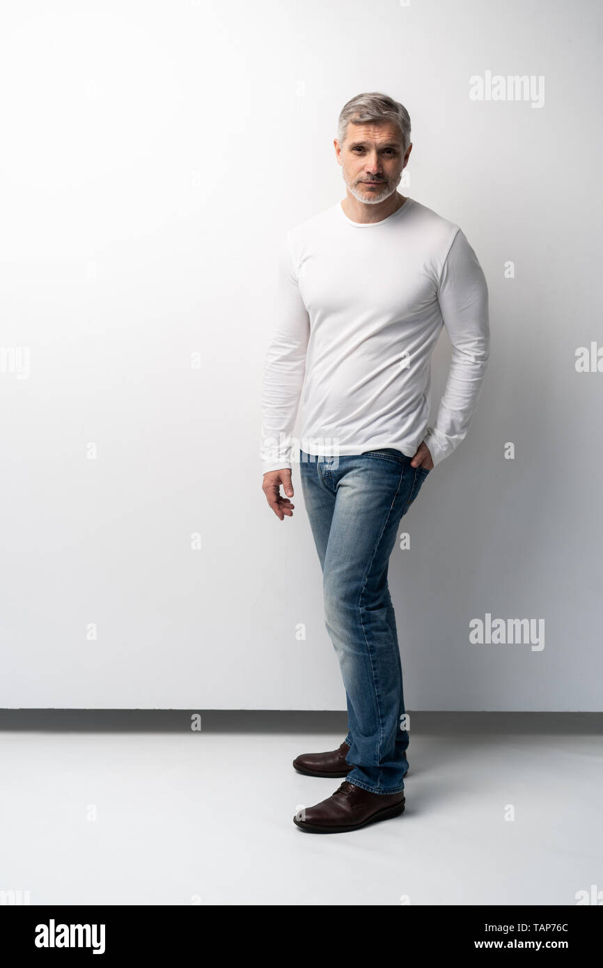 Full body portrait of relaxed mature man standing over white background ...