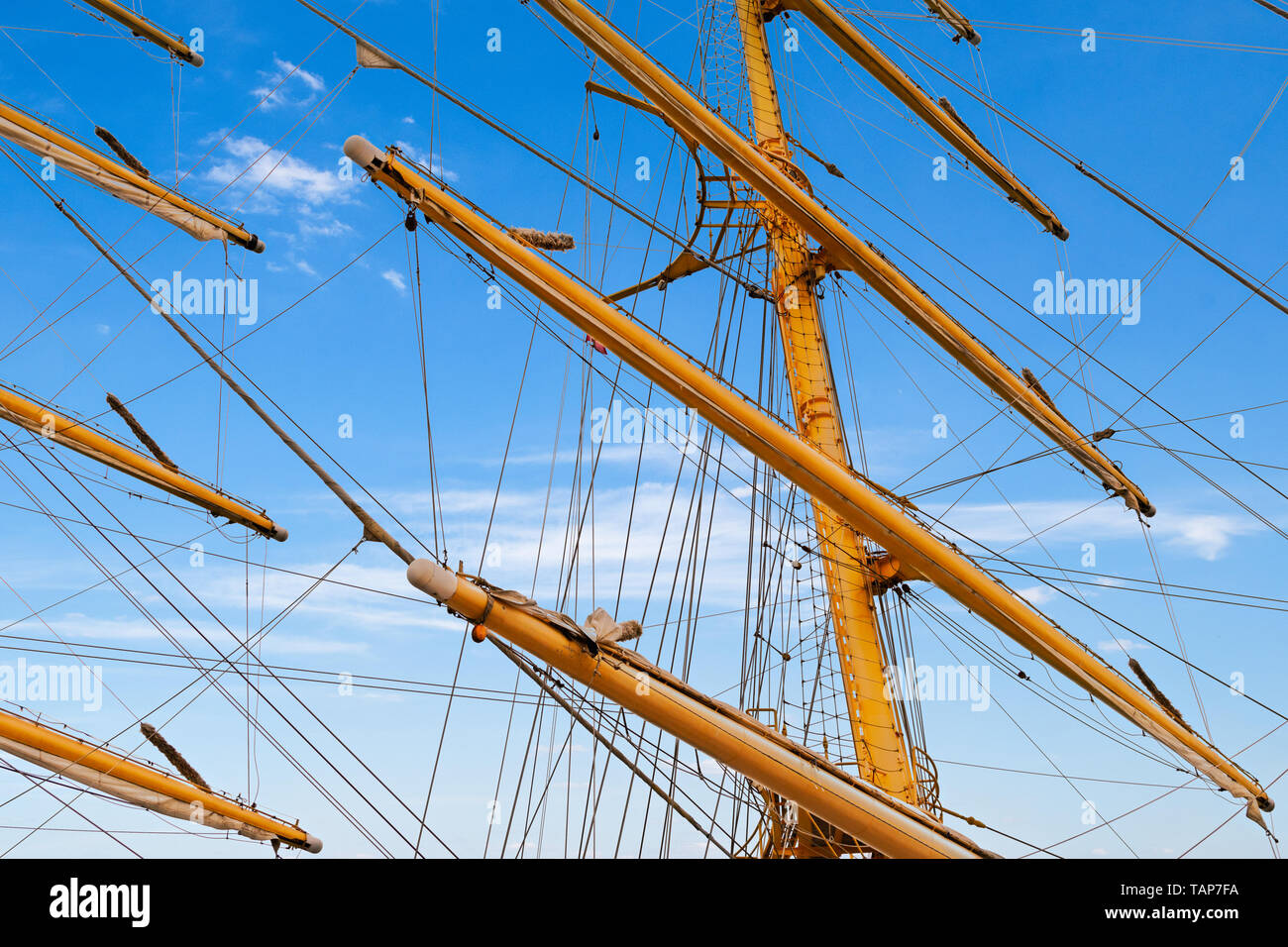 Wooden masts, spars and rigging of the sailboat against the blue ...