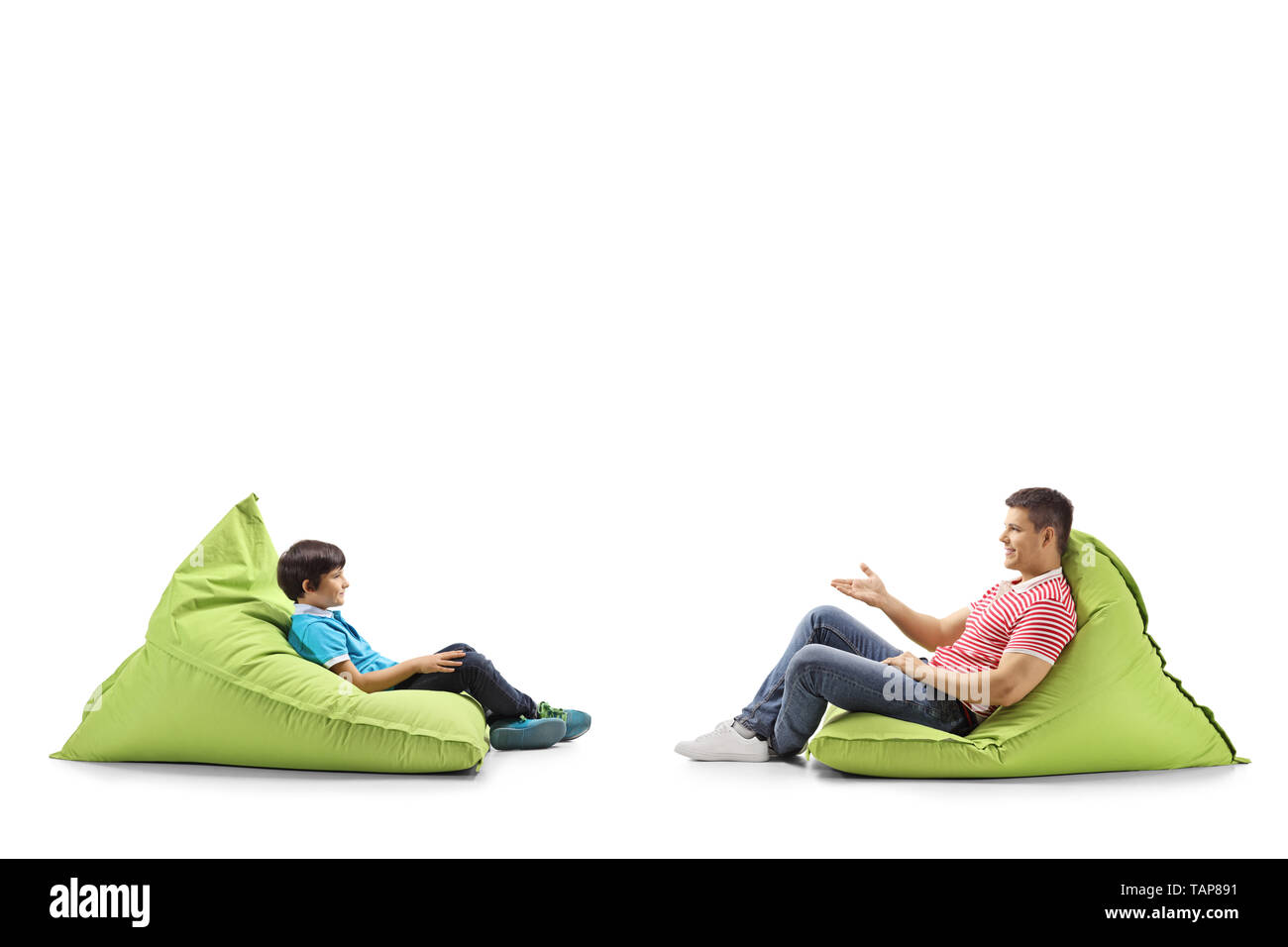 Full length profile shot of a father and son sitting on green bean bags ...