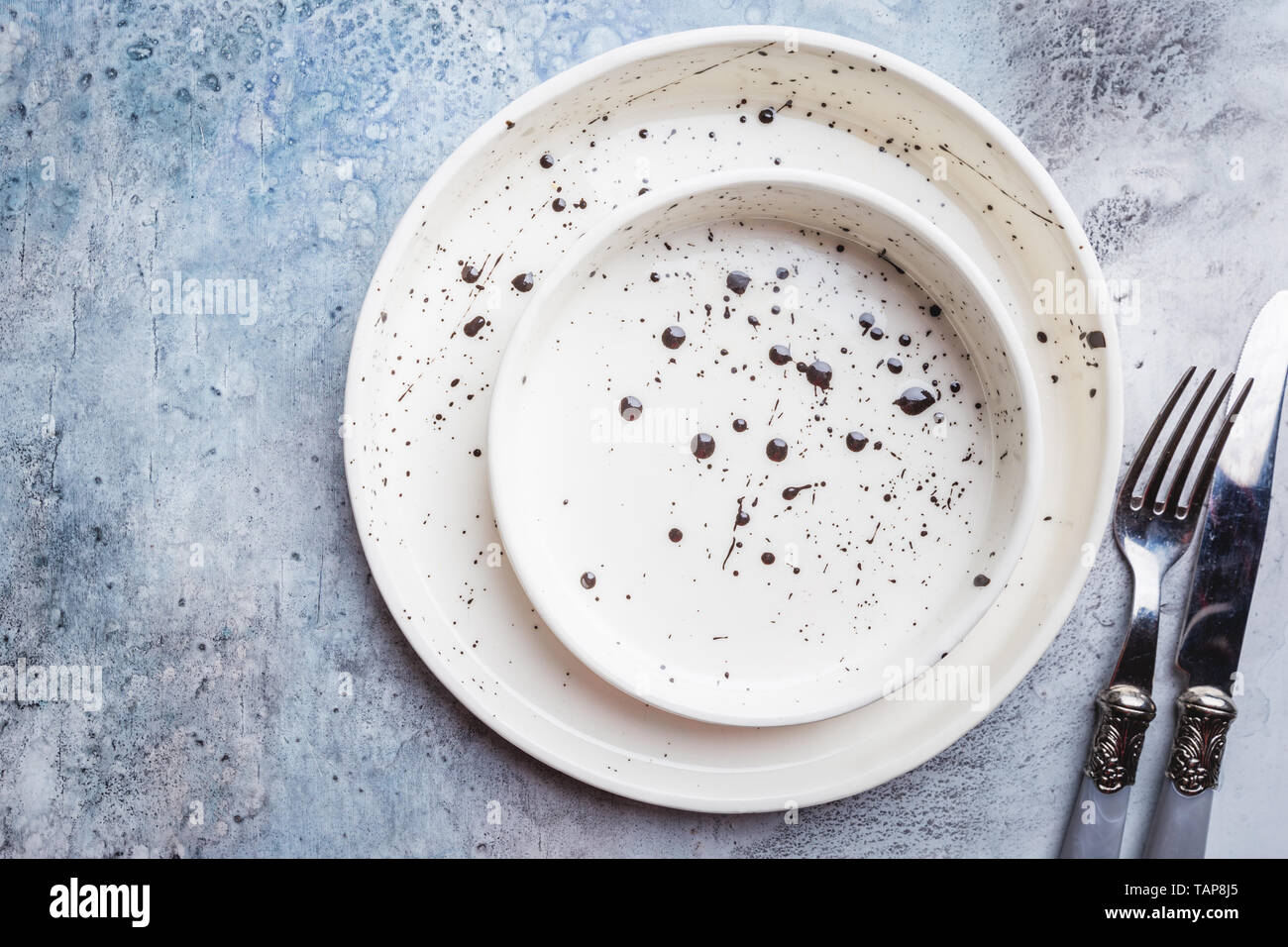 Two handmade empty white plates on blue background. Top view with copy ...