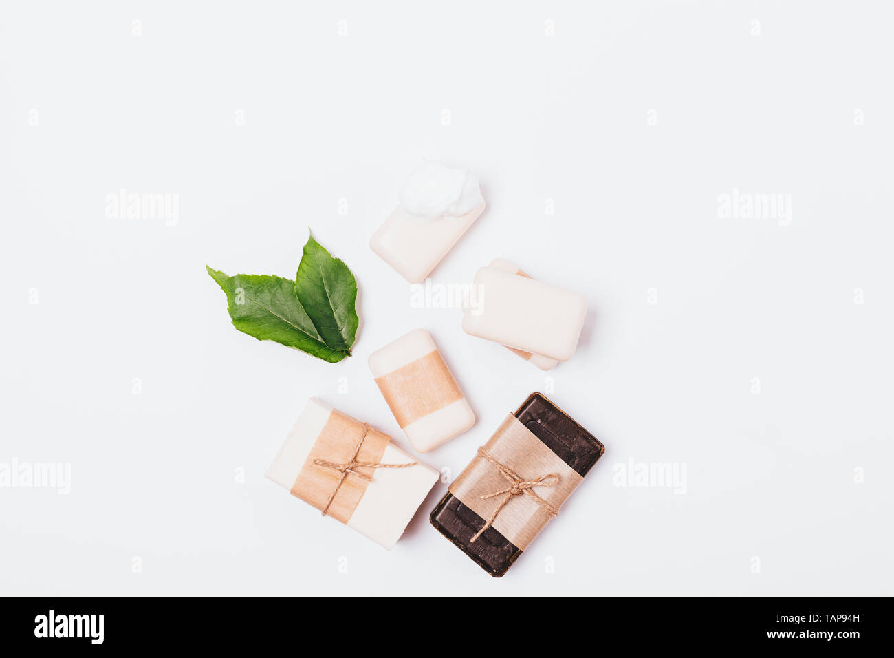 Set of natural handmade soaps of various types next to green leaves on ...