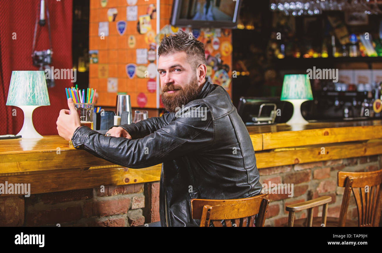 Brutal hipster bearded man sit at bar counter drink beer. Friday ...