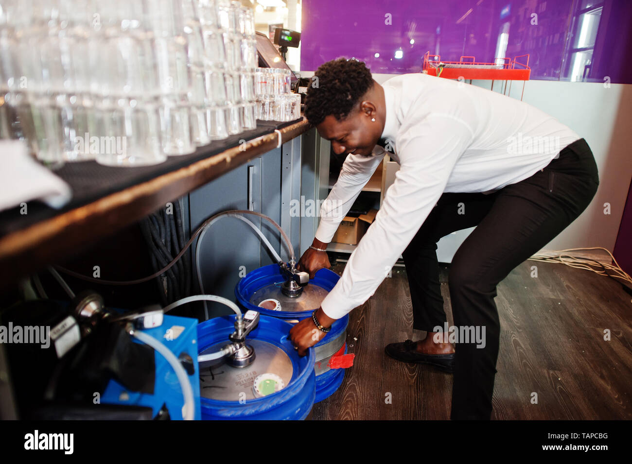 African american bartender at bar with stainless steel beer barrel ...