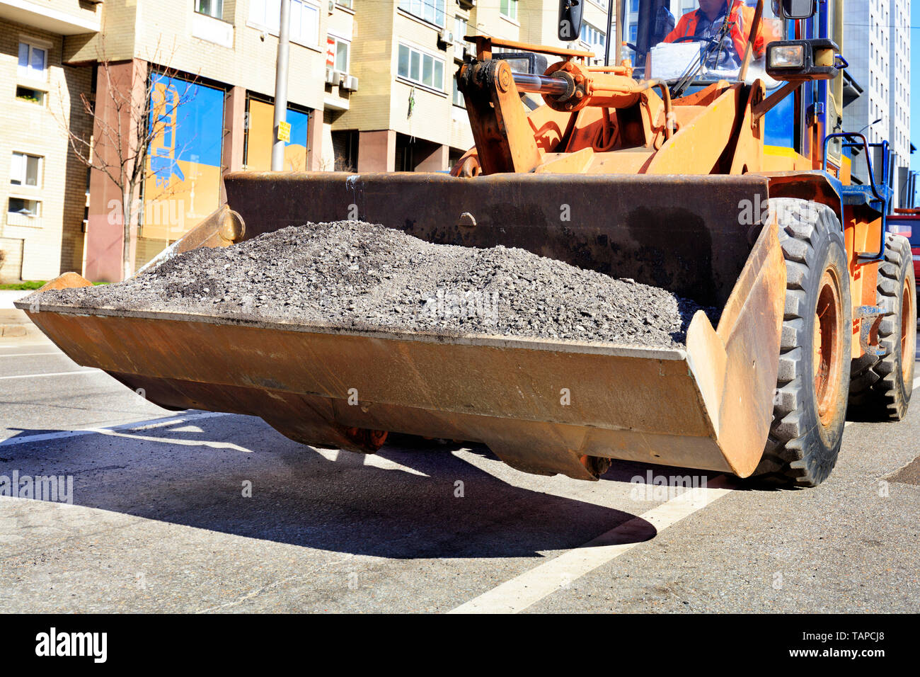 Heavy construction bulldozer carries old worn asphalt in a ladle during ...