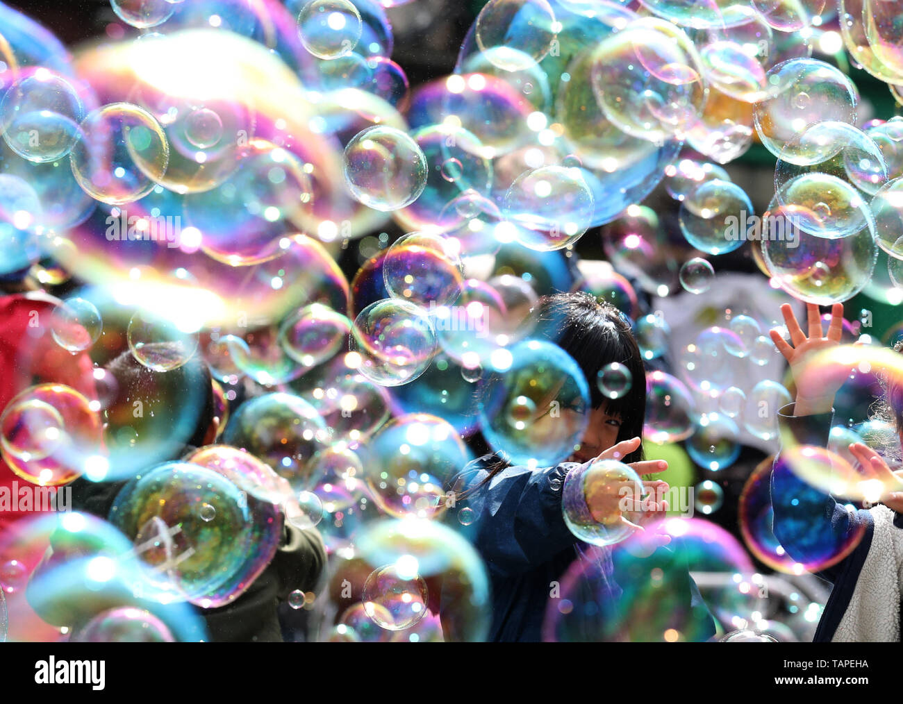 Children try to catch bubbles from a street performer on Bank Holiday ...