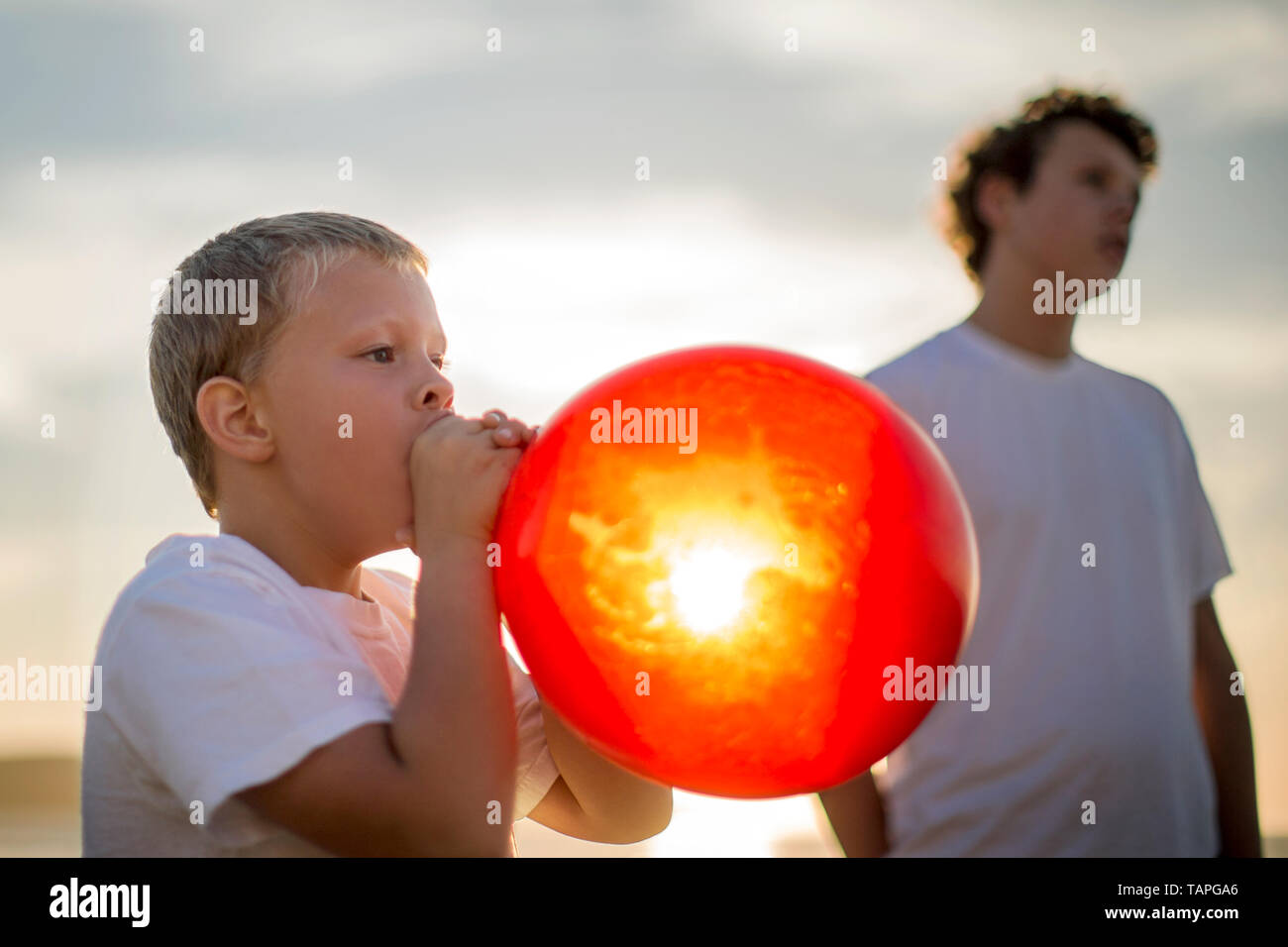 Boy blowing up red balloon hi-res stock photography and images - Alamy