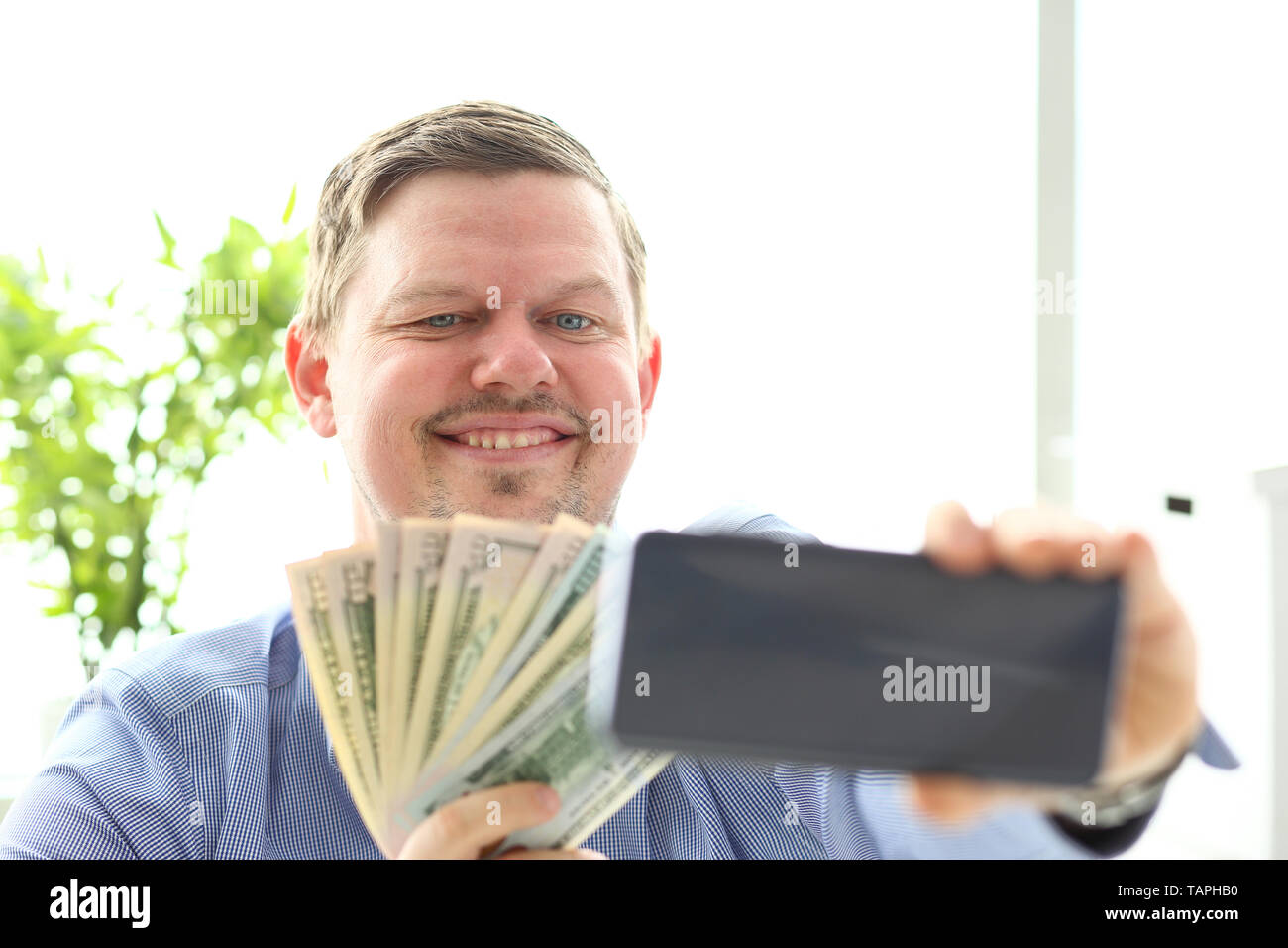 Man making self photo with mobile phone camera posing with pile of ...