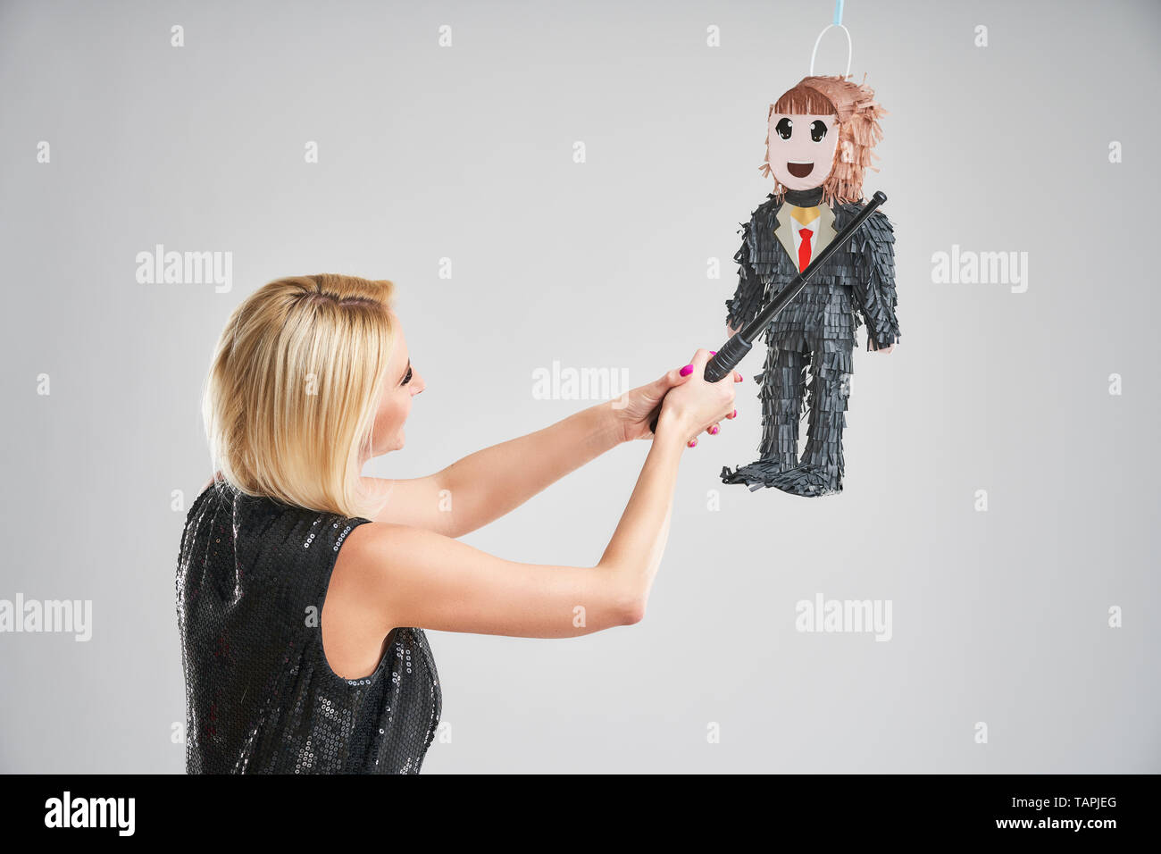 Picture of woman hitting male pinata over grey background Stock Photo ...