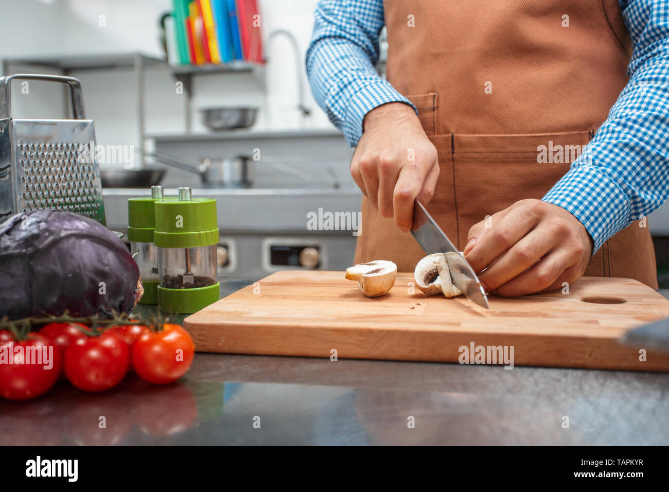 The chef in brown apron cooking in a restaurant kitchen Stock Photo - Alamy