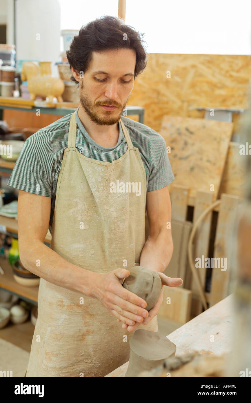 Accurate master. Calm professional clay master warming up ball of fresh ...