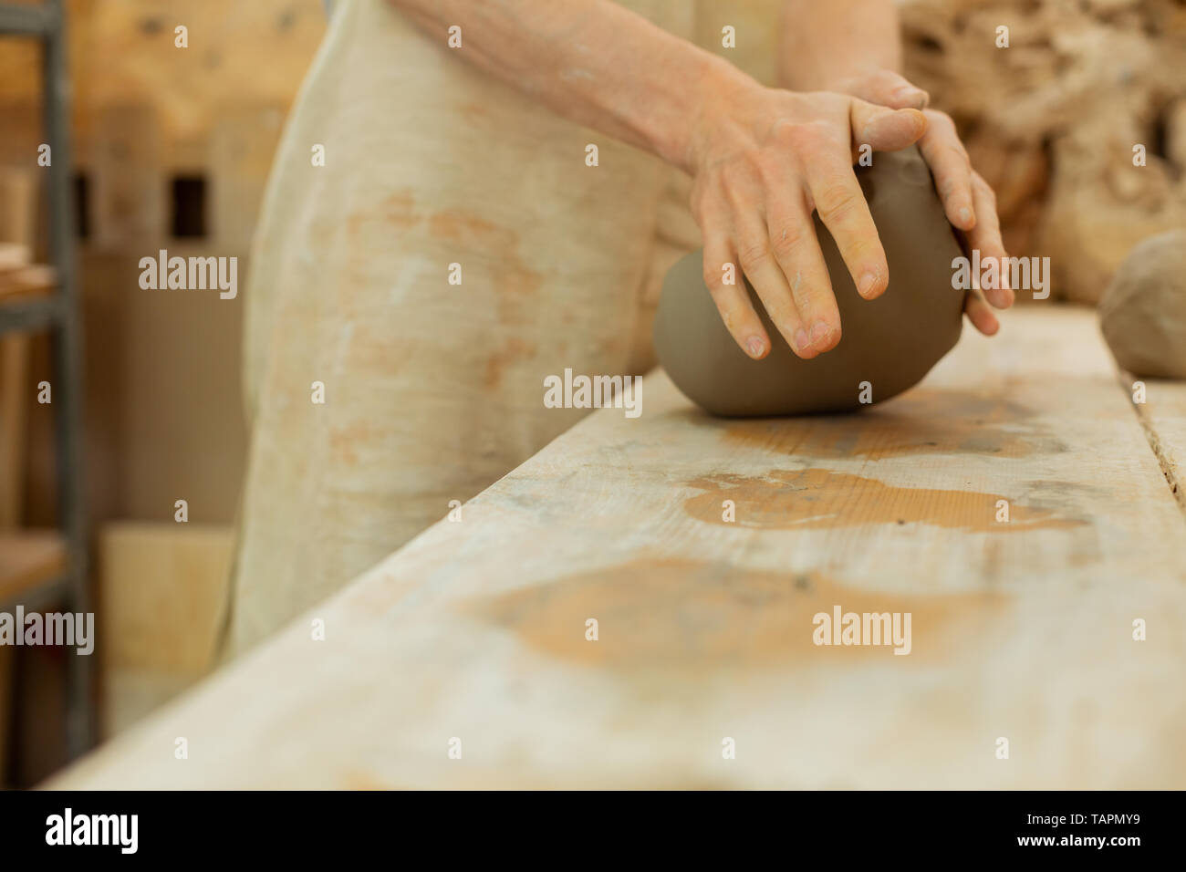 Working in studio. Hard-working strong man pressing big part of clay ...