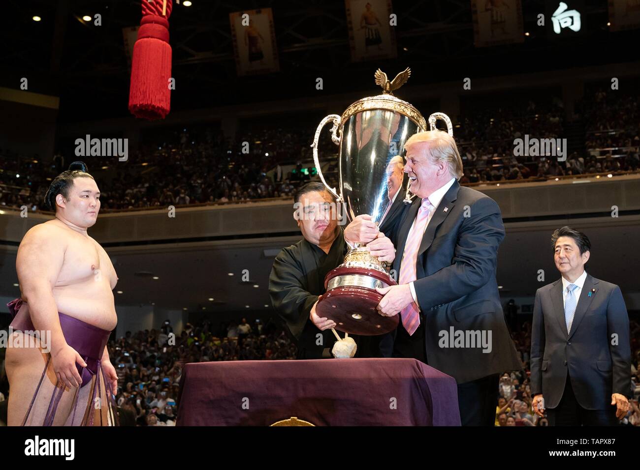 U.S. President Donald Trump is helped with the 60-pound Presidents Cup ...